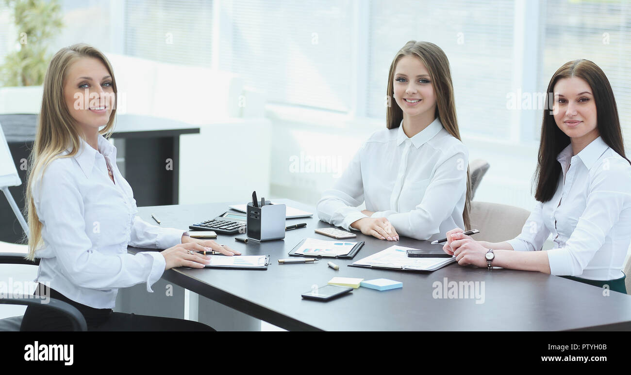 three young employees sitting behind a Desk Stock Photo - Alamy