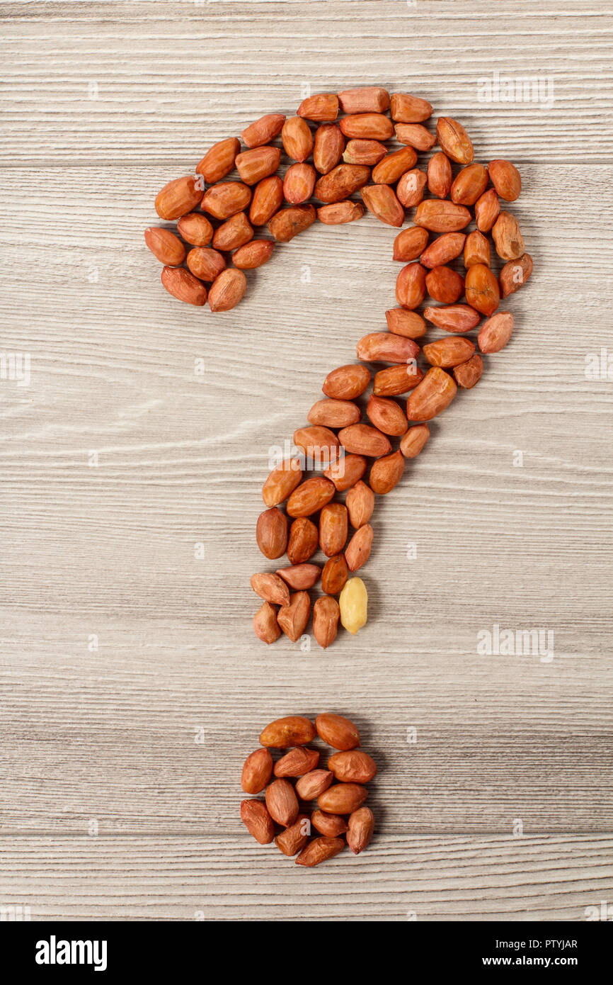 Question mark sign made of peanuts on grey wooden background. Top view ...