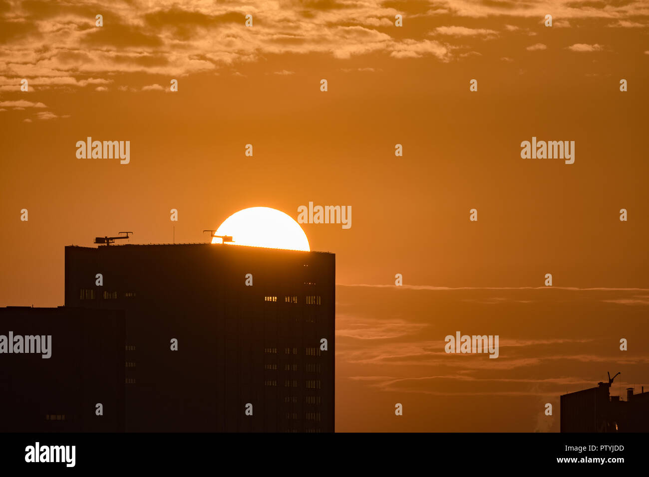 Sun rising behind a building close up with orange sky in Chengdu, China ...