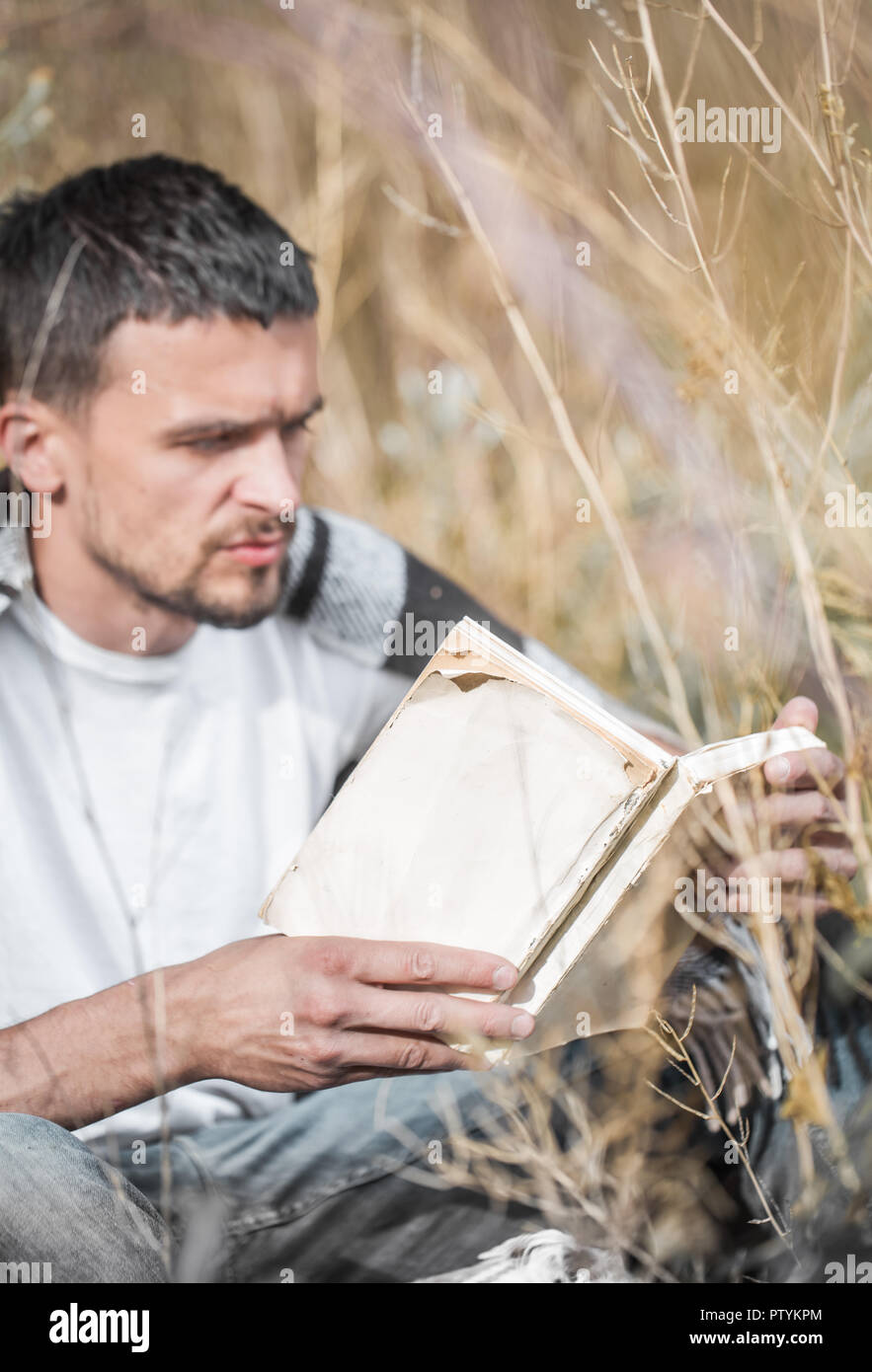young handsome man on the field reading a book, the concept of rest and ...