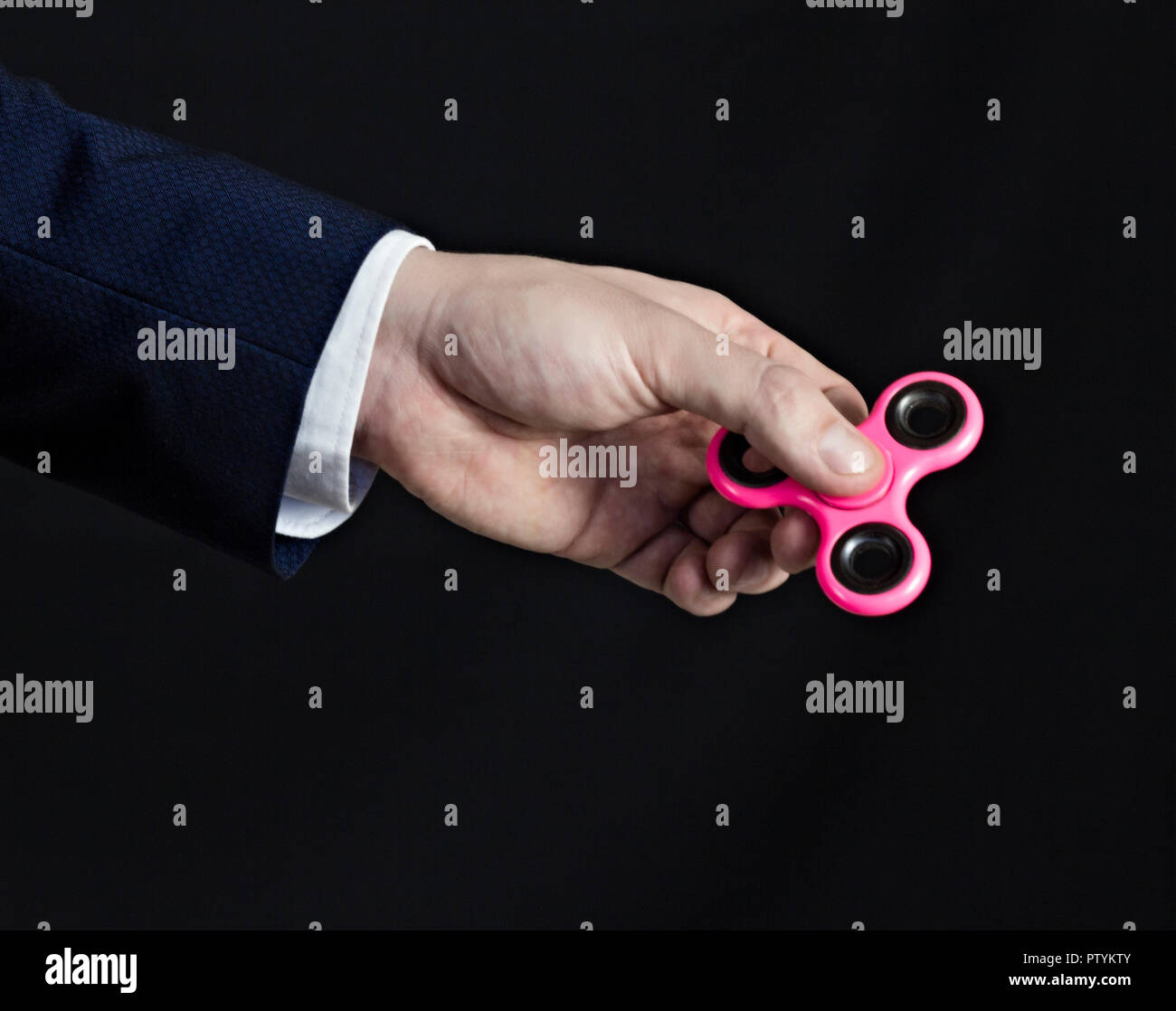 A man in a suit holds a spinner in his hand, a black background, a ...