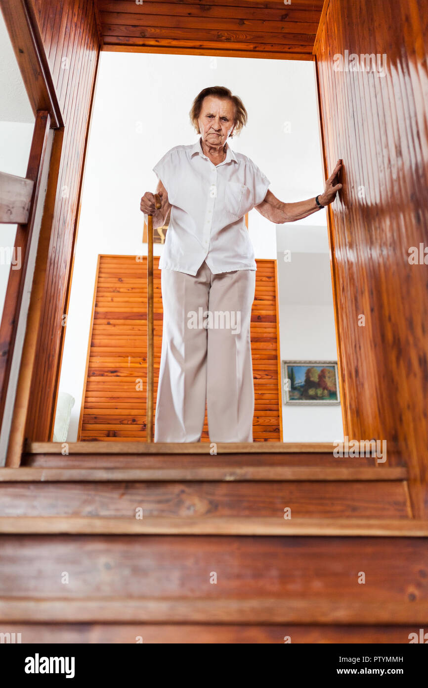 Elderly woman at home using a walking cane to get down the stairs Stock ...