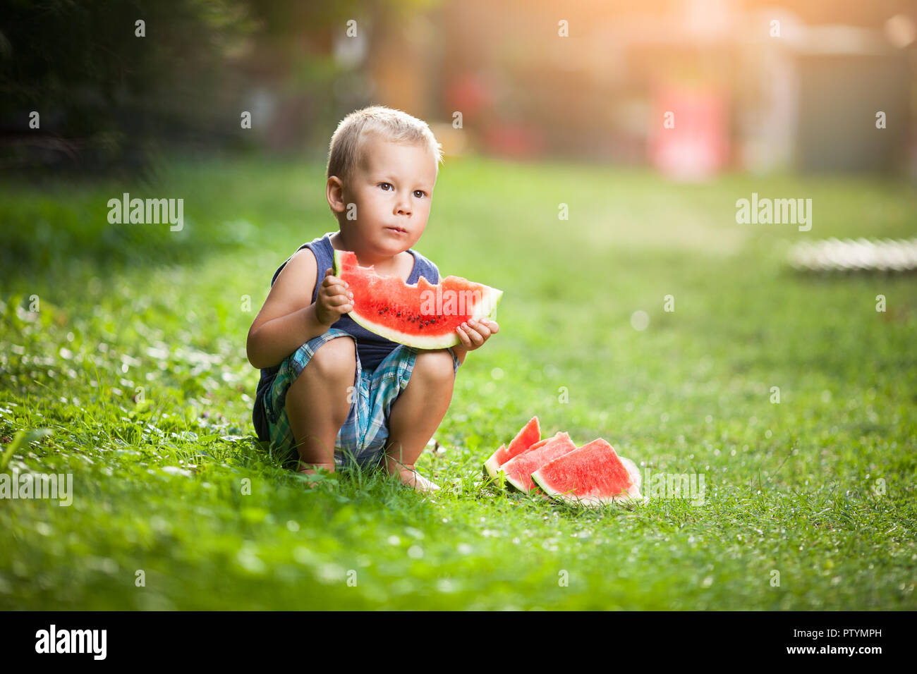 Cute toddler sitting outdoords and eating a slice of watermelon Stock ...