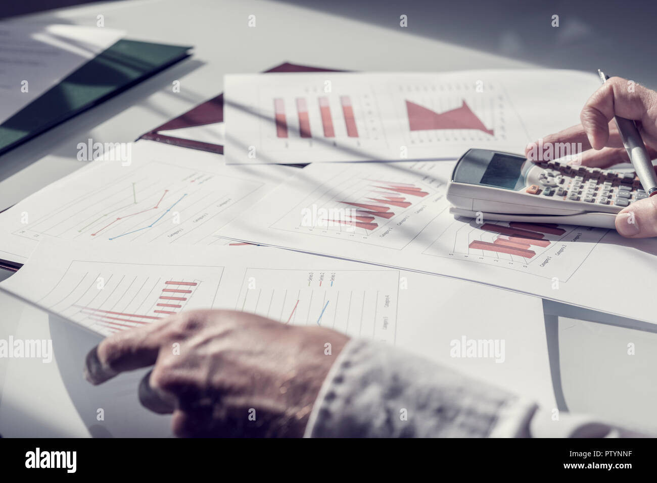 Hands of unidentifiable person checking facts on various printed paper ...