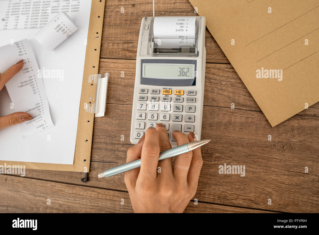 Top view of female accountant using adding machine with documents and ...