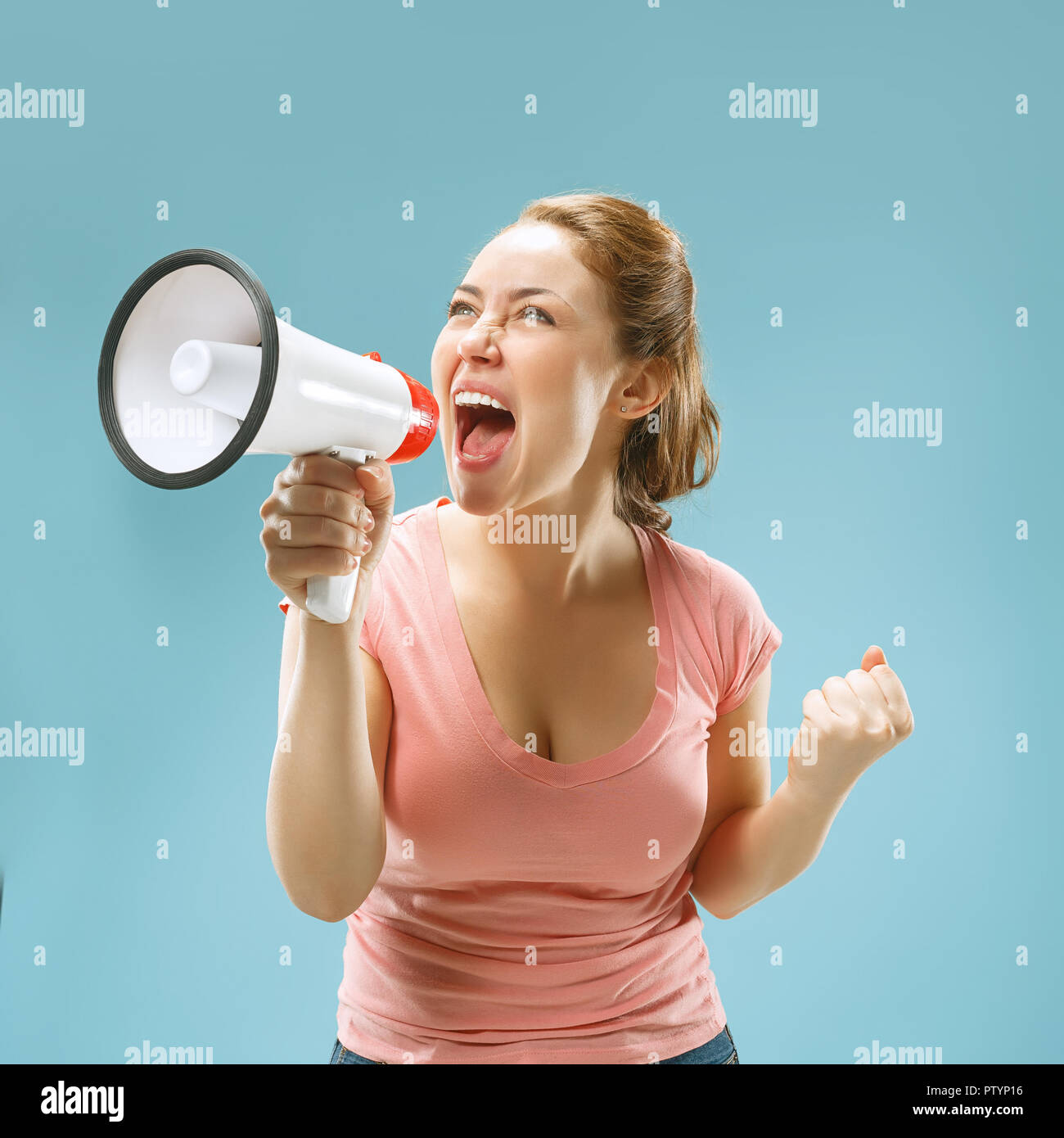 Woman making announcement with megaphone at blue studio Stock Photo - Alamy