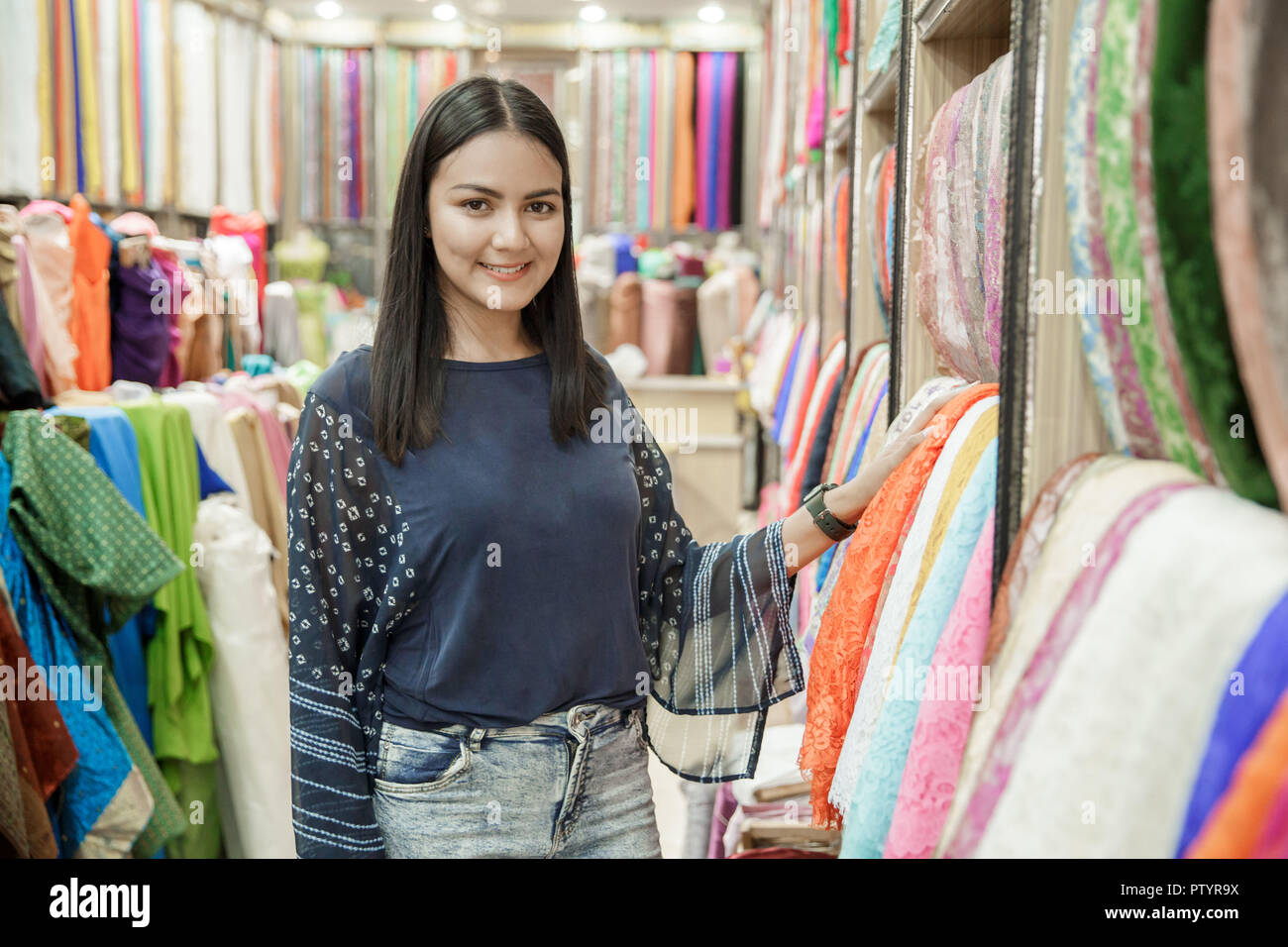 portrait of beautiful woman looking around fabric at fabric store Stock ...