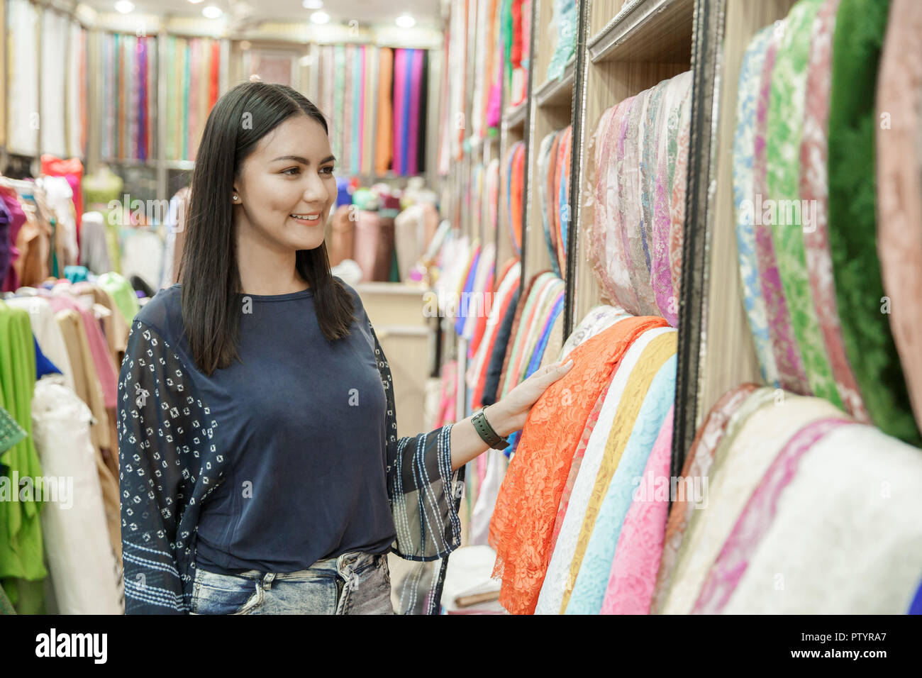 portrait of beautiful woman looking around fabric at fabric store Stock ...