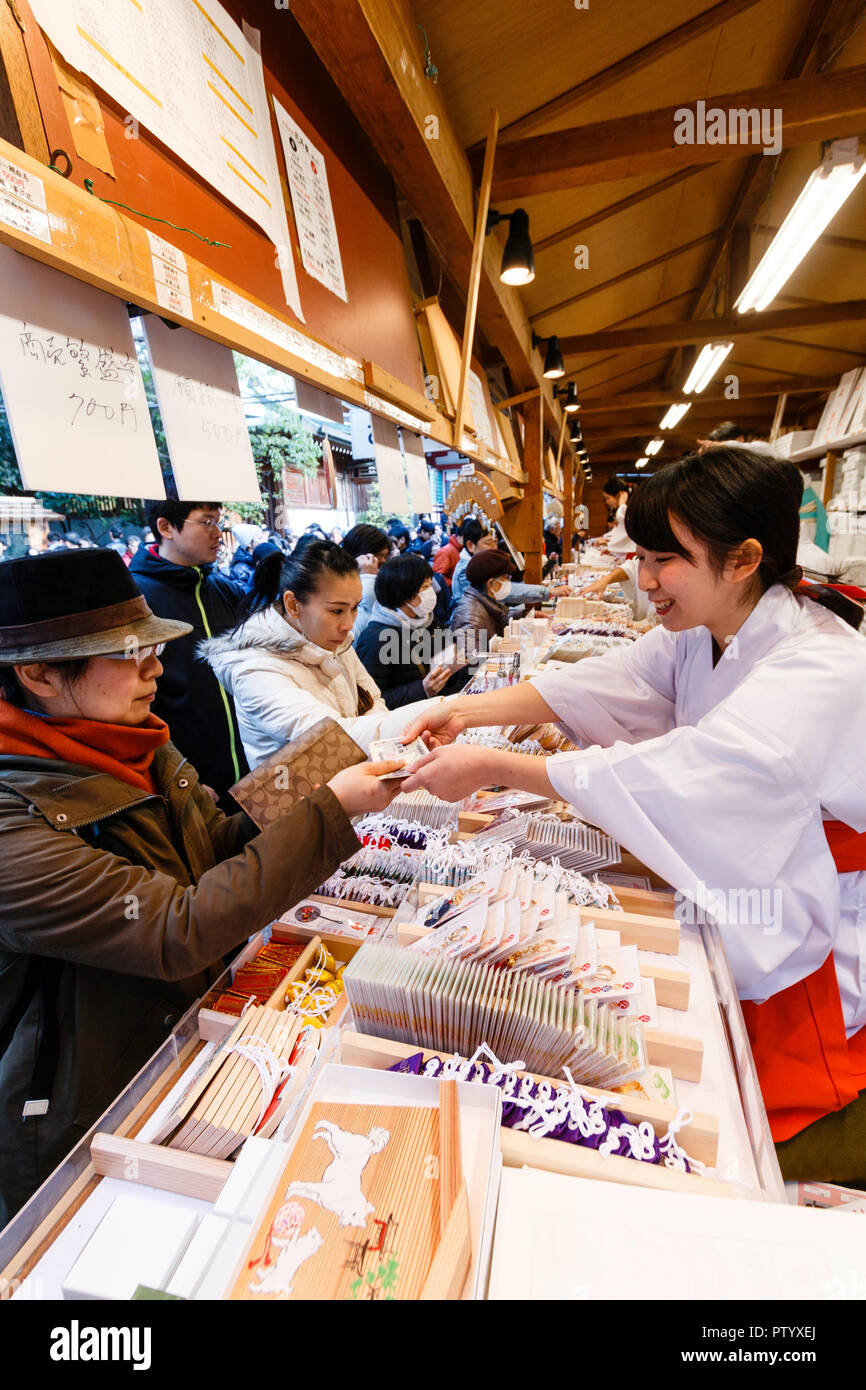 Japanese new year, shogatsu. Shrine Maiden, Miko, handing over omamori ...