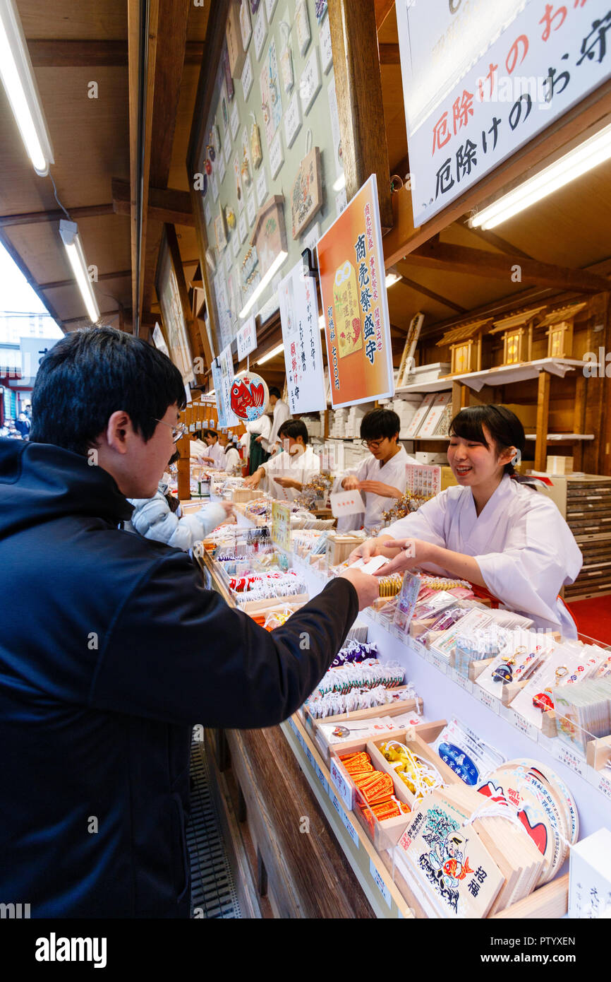 Japanese new year, shogatsu. Shrine Maiden, Miko, handing over omamori ...