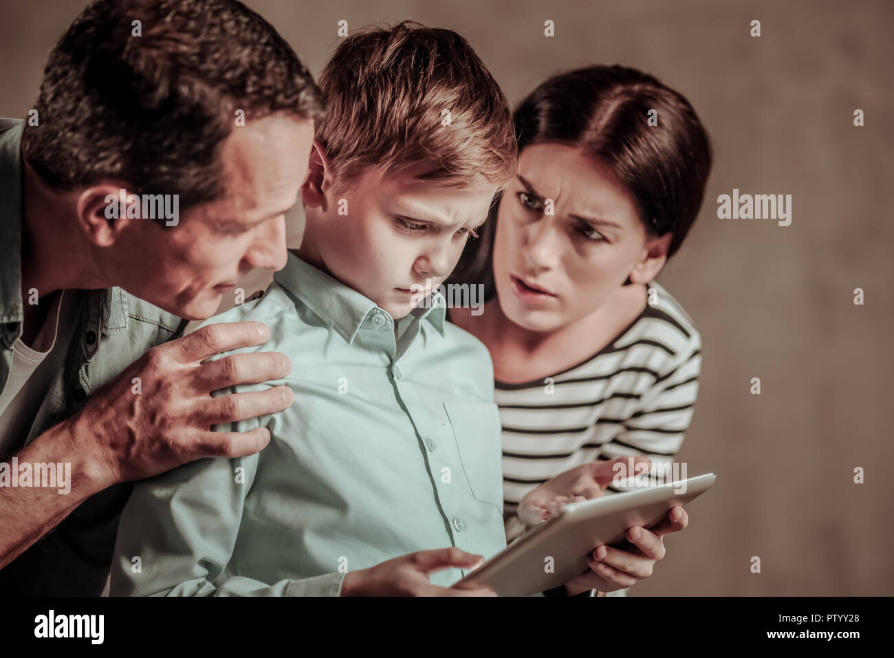 Negative delighted kid standing between his parents Stock Photo - Alamy