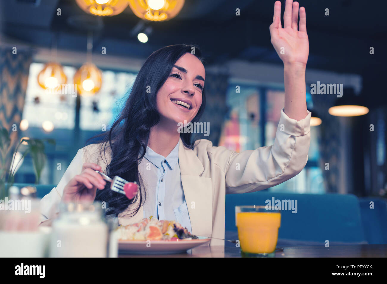 Pretty longhaired female person calling her waiter Stock Photo - Alamy