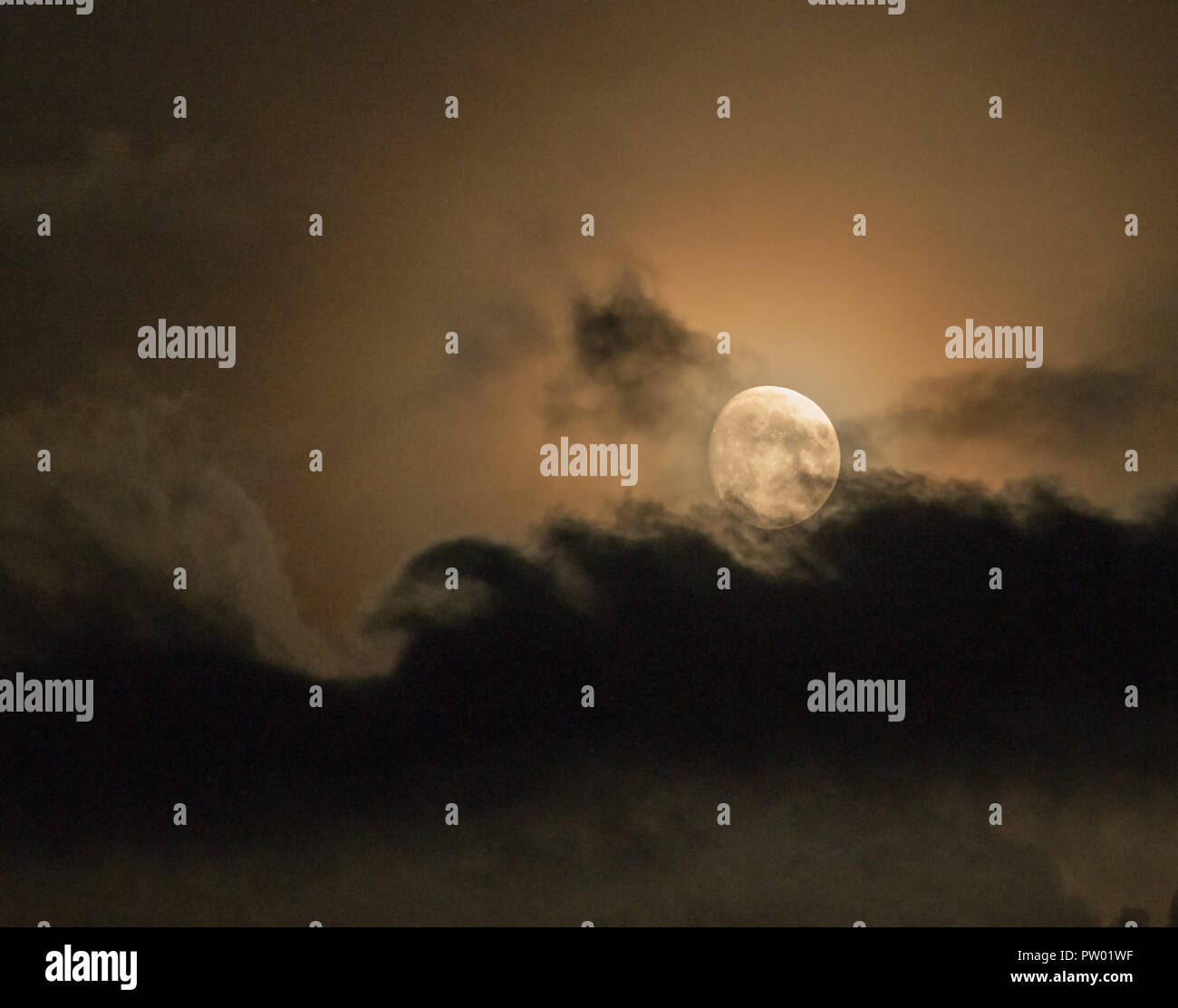 Yellow moon between heavy clouds in the night sky Stock Photo - Alamy