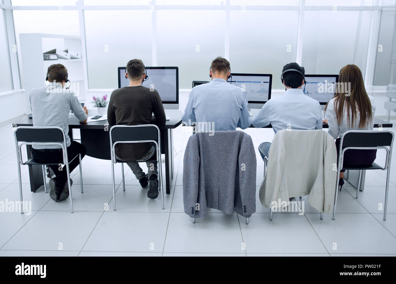 rear view.a group of call center employees sitting at the Desk Stock ...