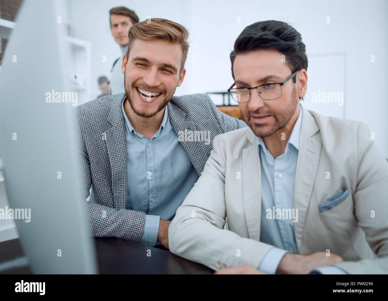 smiling colleagues looking at the computer monitor Stock Photo - Alamy
