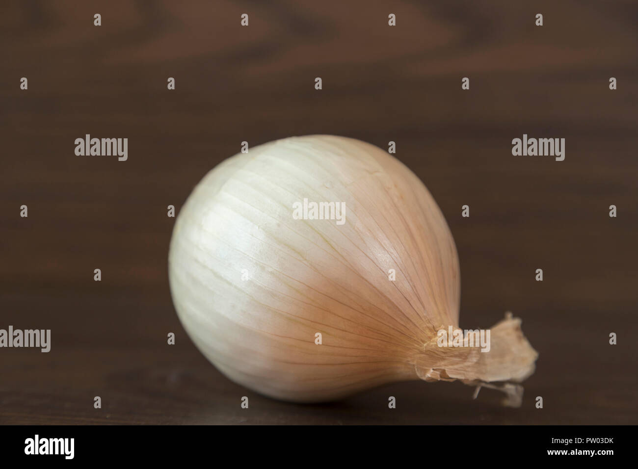 Onion located in front of a brown wooden background, we can see the ...