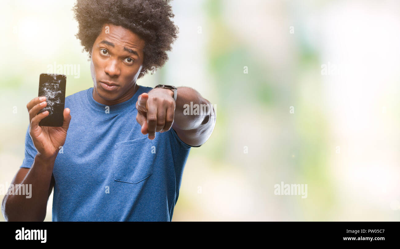Afro american man holding broken smartphone over isolated background ...