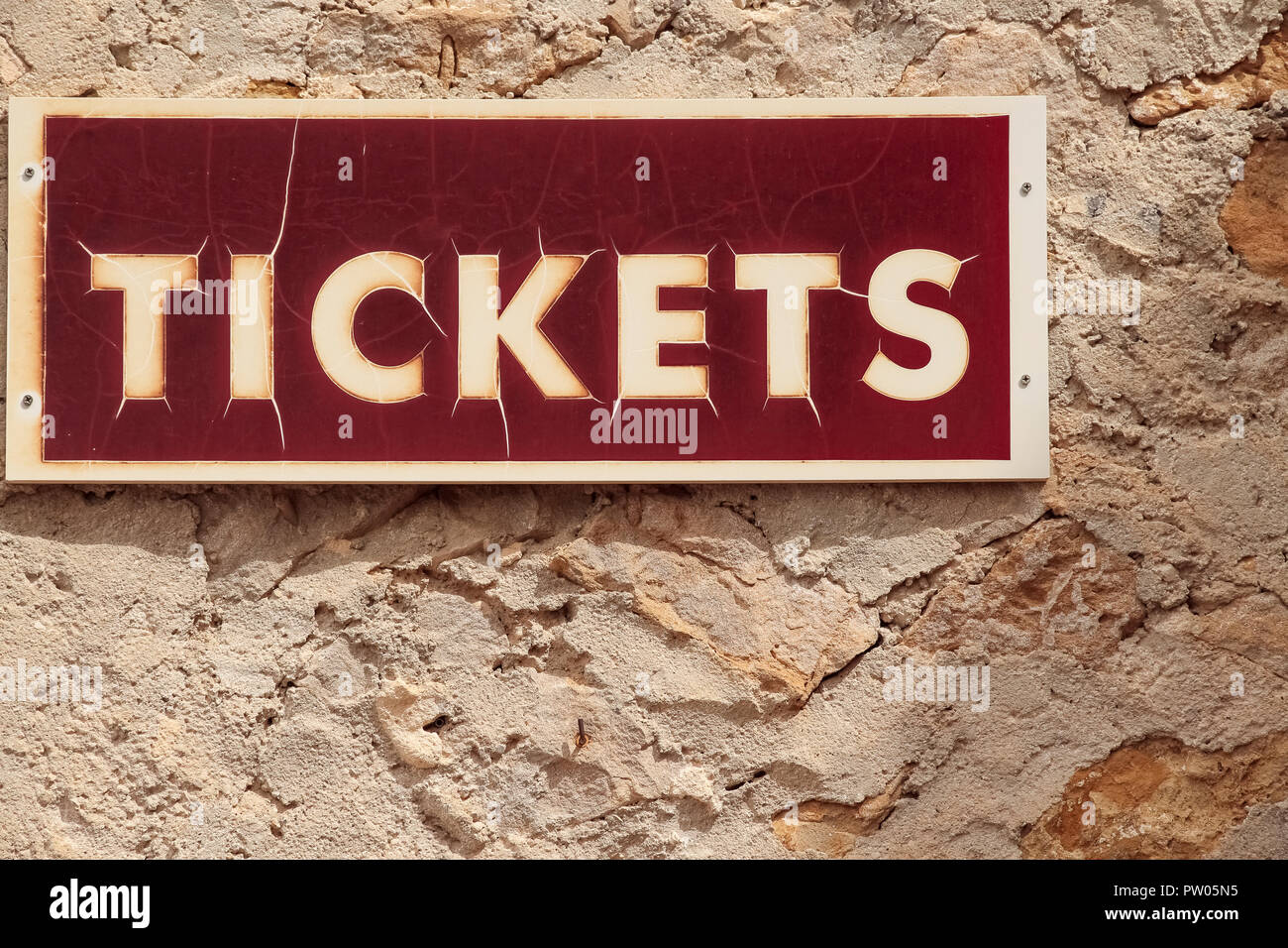 rectangular red signboard that indicates the sale of tickets on a wall ...
