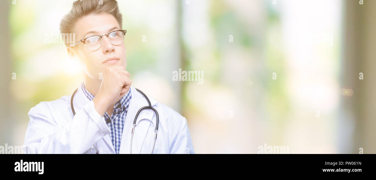 Young handsome blond doctor serious face thinking about question, very ...