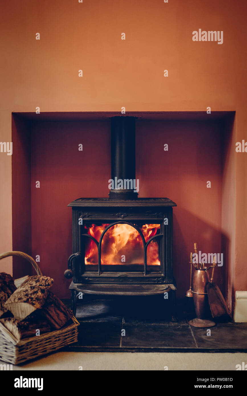 Roaring log fire with basket of logs and companion set Stock Photo - Alamy