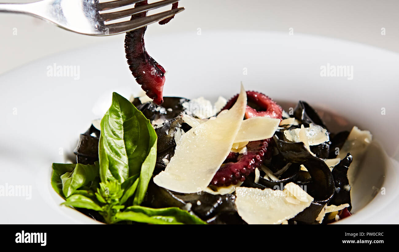 Pasta with black cuttlefish ink, octopuses and parmesan Stock Photo - Alamy