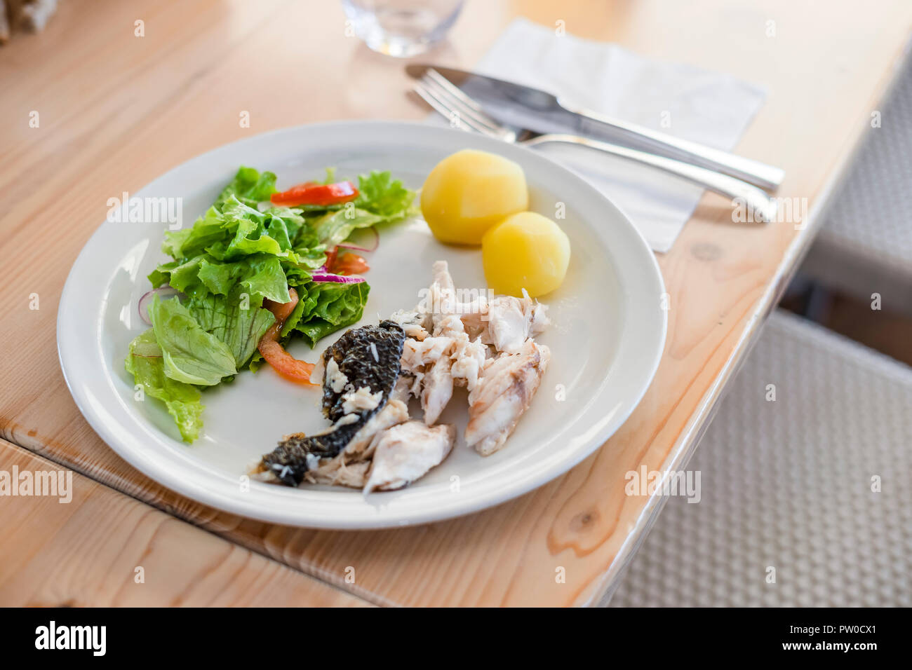 Freshly barbecued golden fish with cooked potatoes and salad in the ...