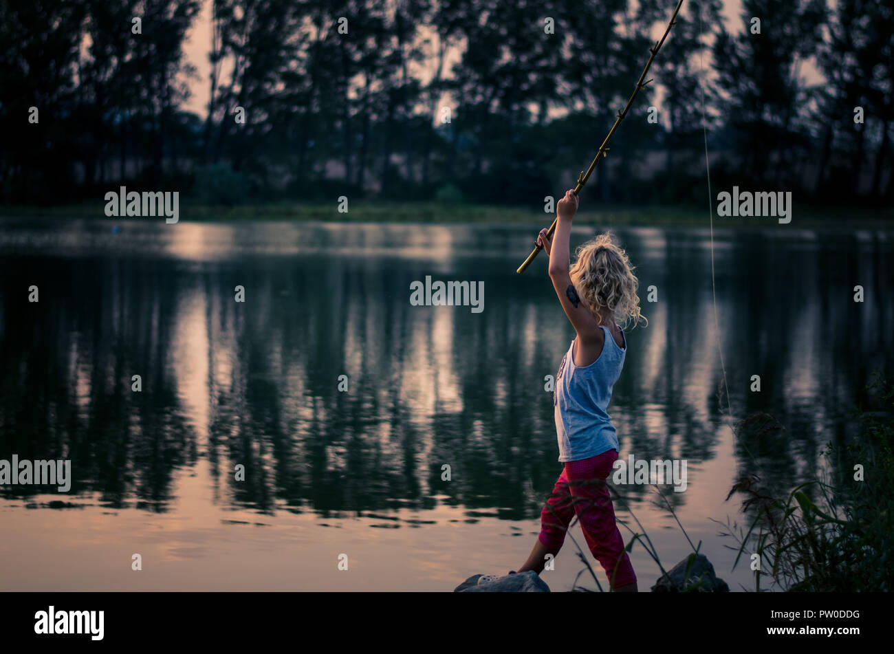 adorable little girl fishing with home made fishing rod at the pond at ...