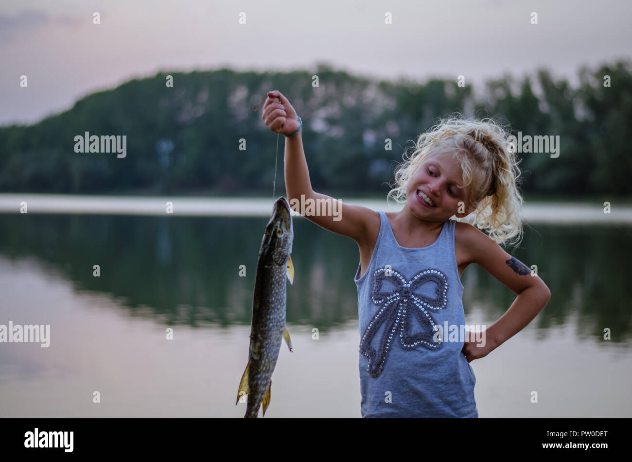 adorable little girl with fish at the pond at the sunset Stock Photo ...
