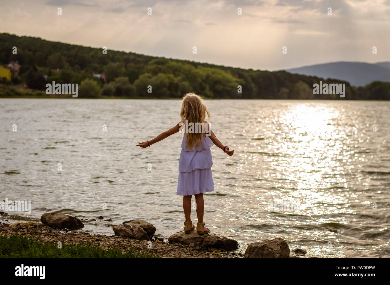 adorable little girl in dress at the pond outdoors in the afternoon ...
