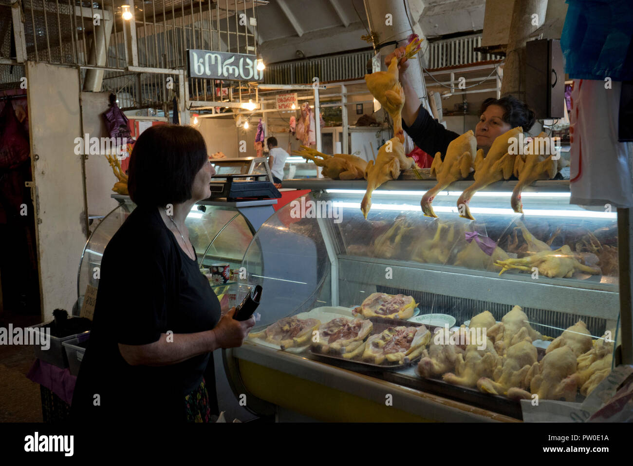 Customer buying at a chicken food counter at the market in Kutaisi ...
