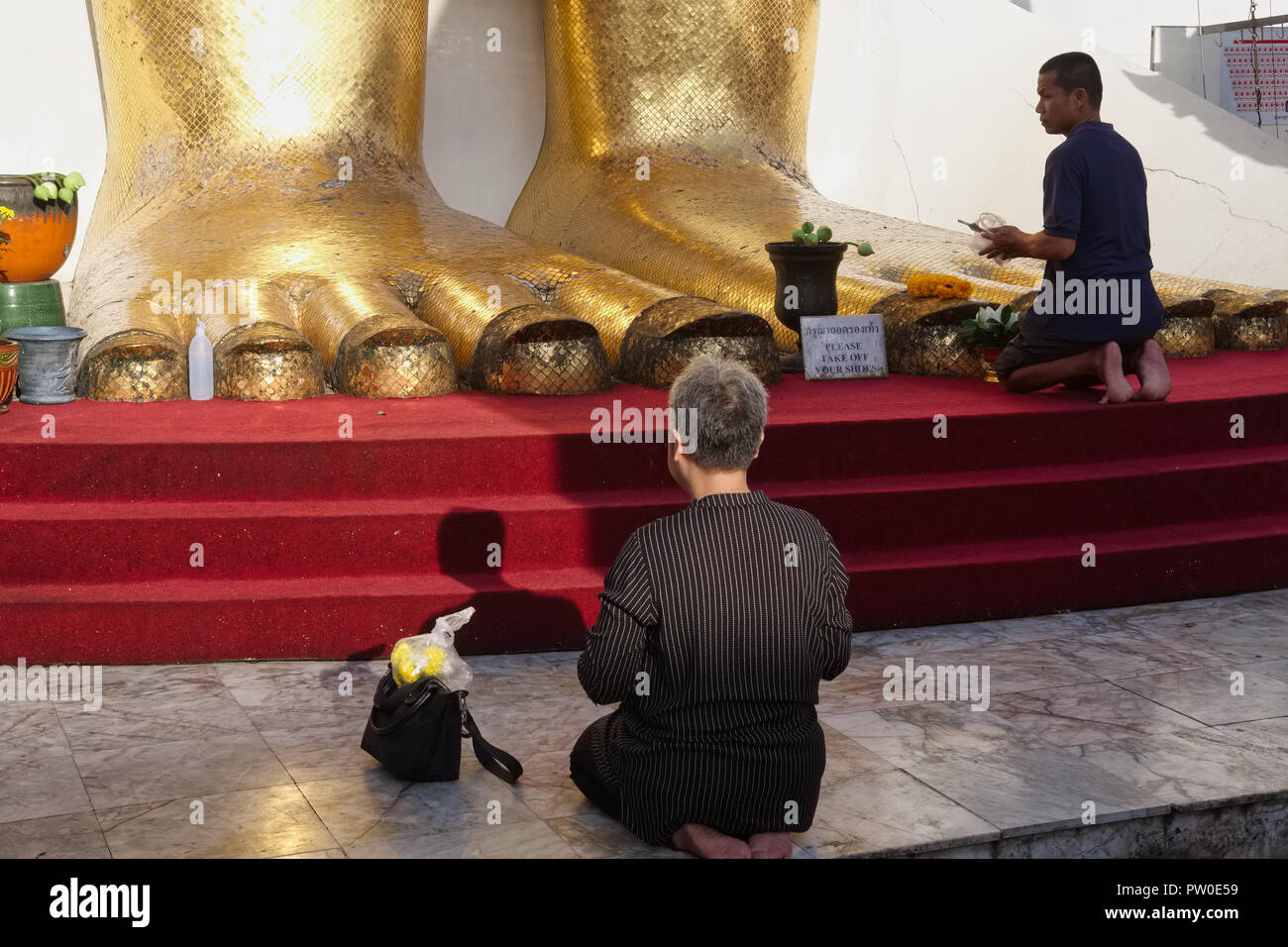 Worshippers at the feet of the giant Buddha statue at Wat Indraviharn ...