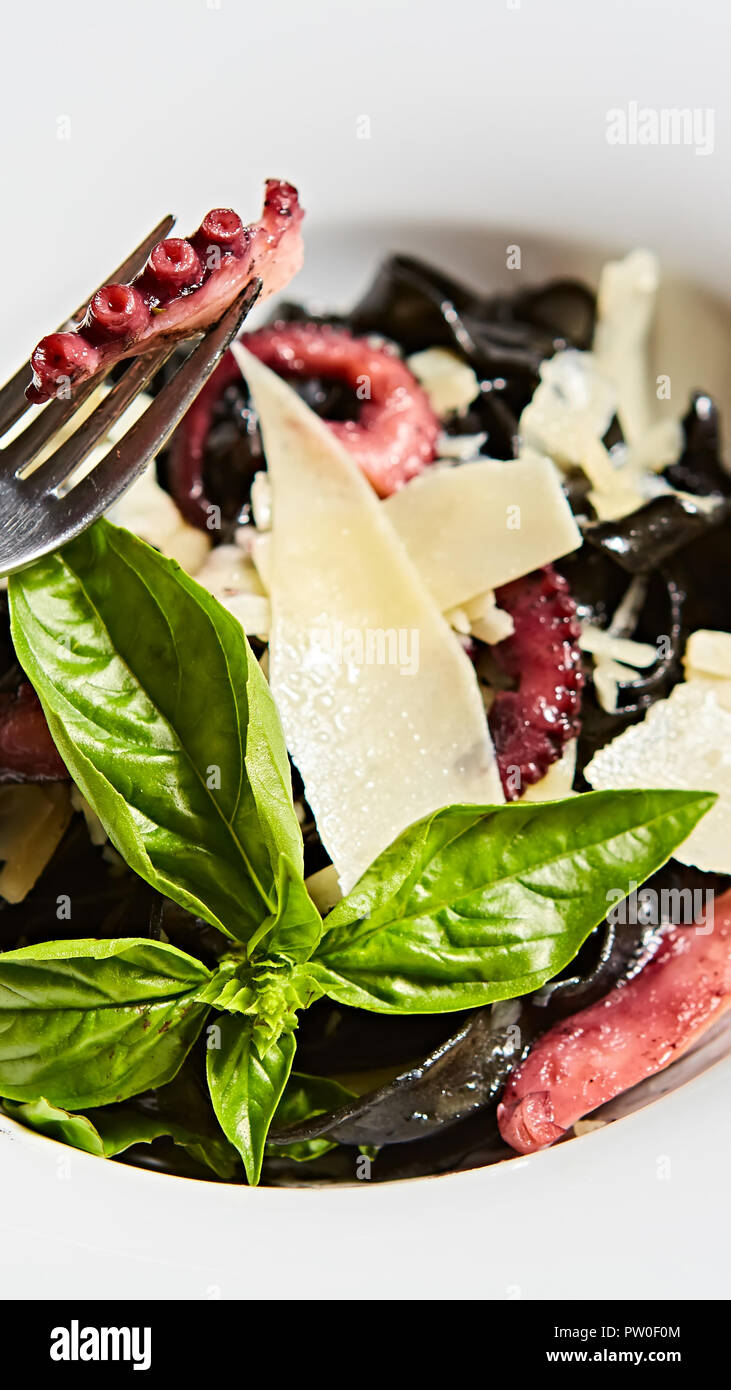 Pasta with black cuttlefish ink, octopuses and parmesan Stock Photo - Alamy