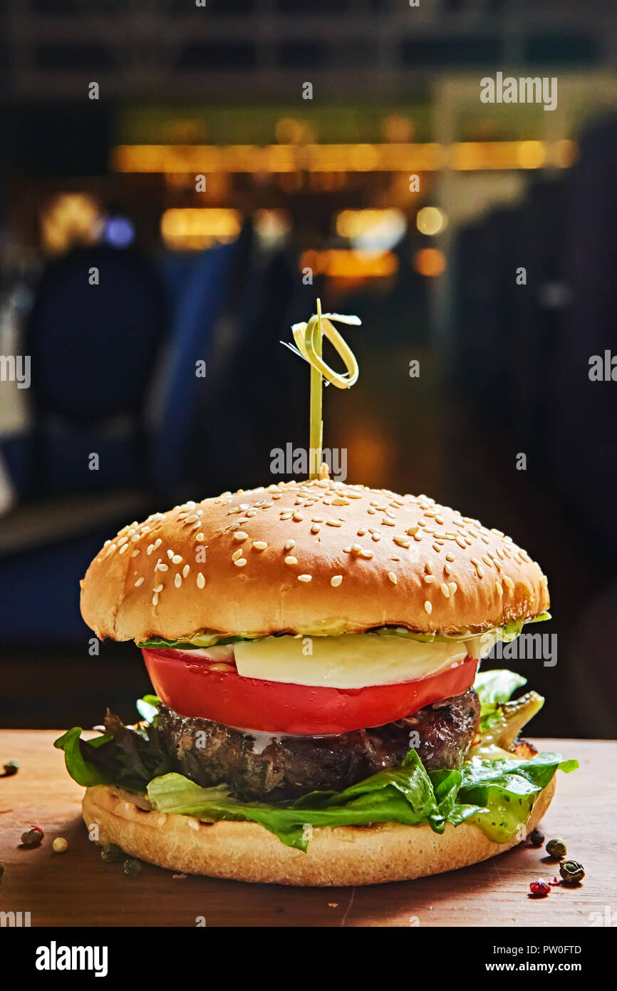 Beef burger with lettuce and mayonnaise served on a rustic wooden table ...