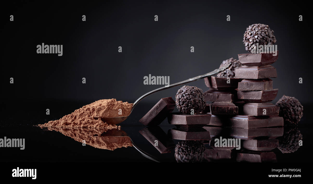 Chocolate candies, broken chocolate pieces and spoon with cocoa powder ...