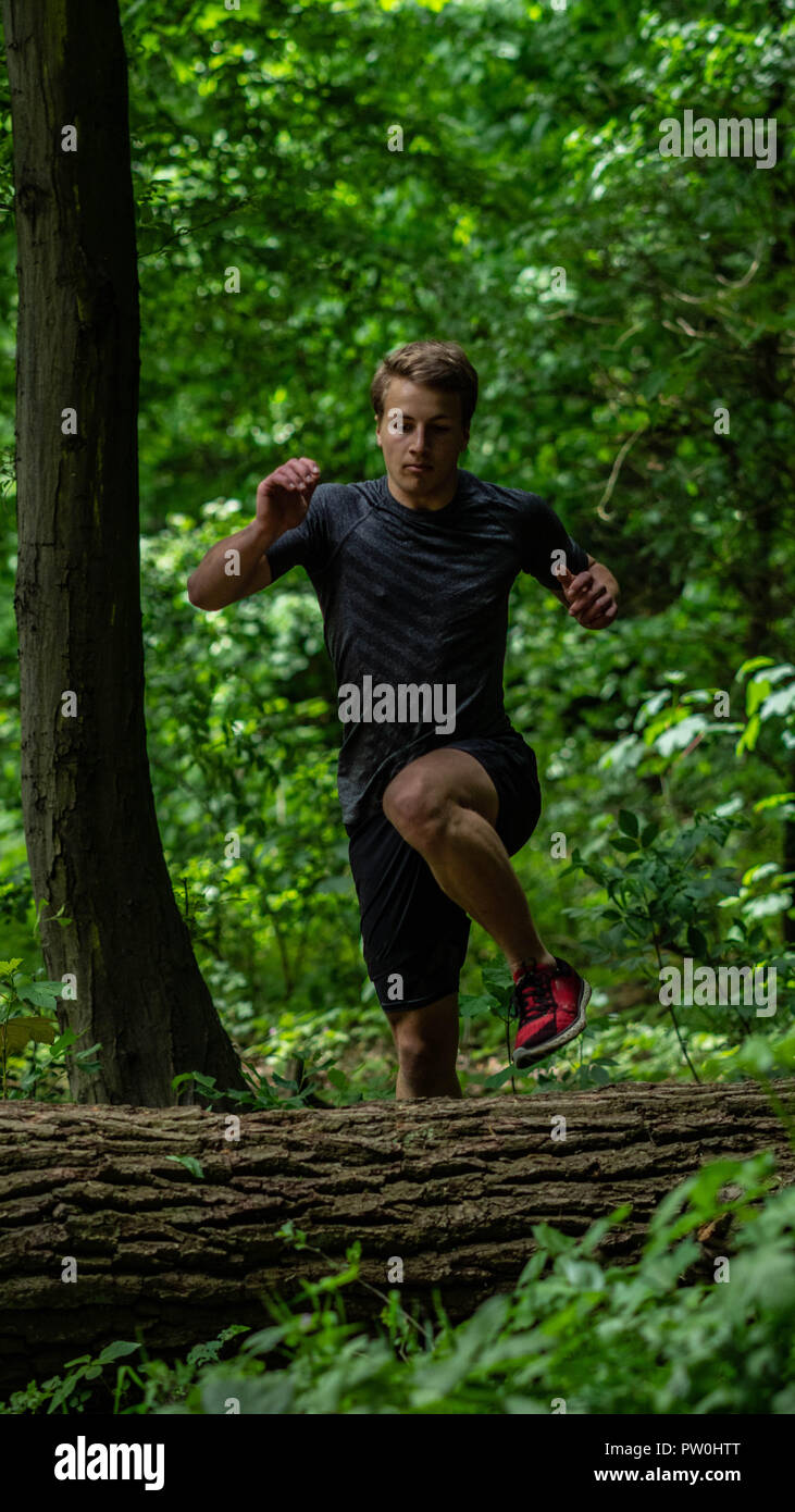 the guy jumps over a large log while participating in an ocr race Stock ...