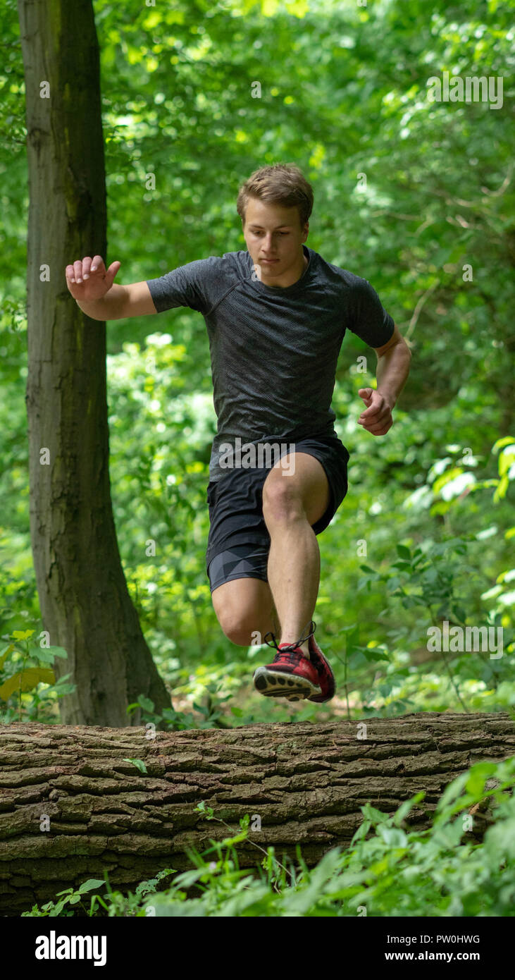 the guy jumps over a large log while participating in an ocr race Stock ...