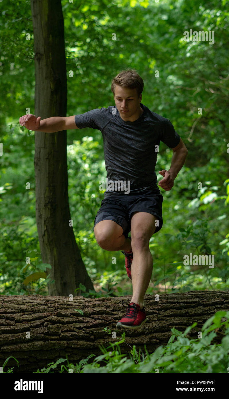 the guy jumps over a large log while participating in an ocr race Stock ...