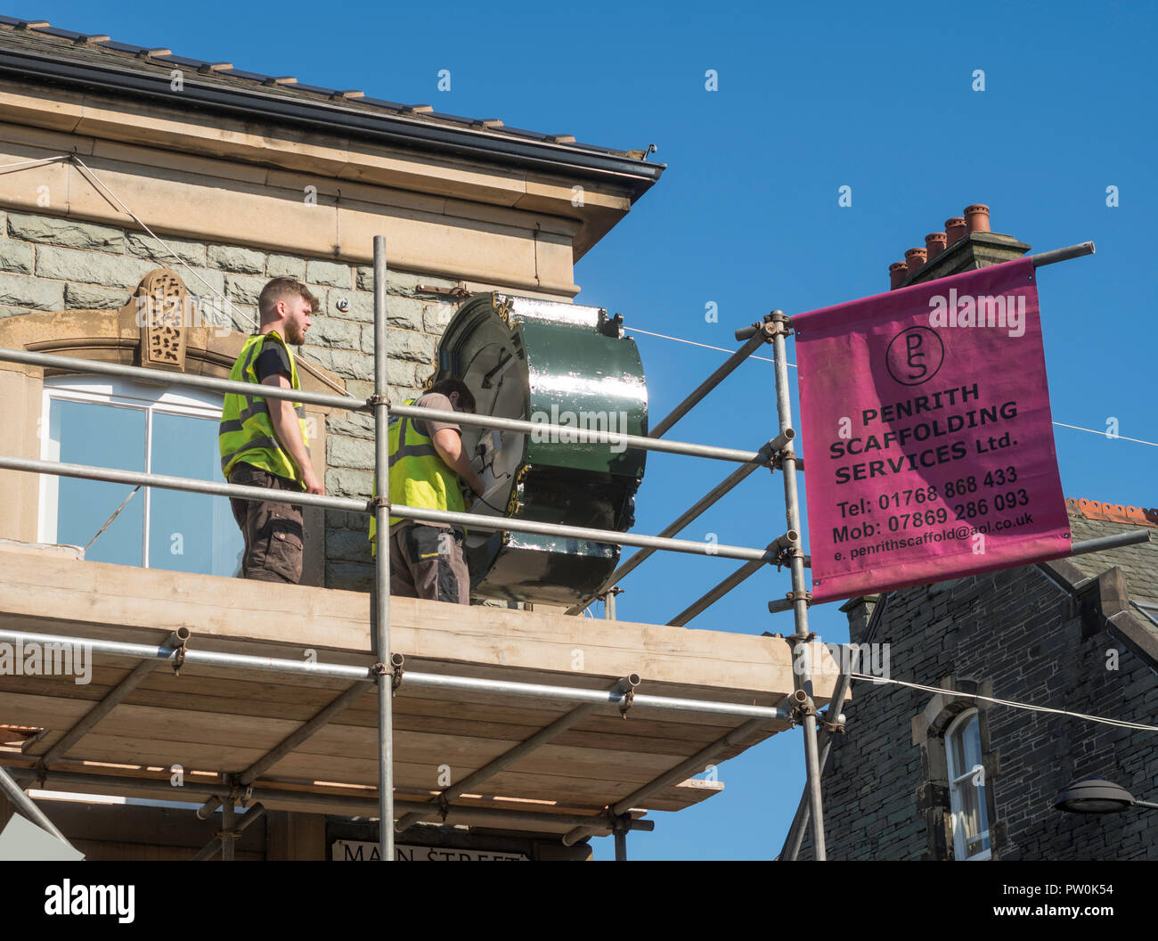 Workman refurbishing Keswick town hall clock, Cumbria, England, UK ...