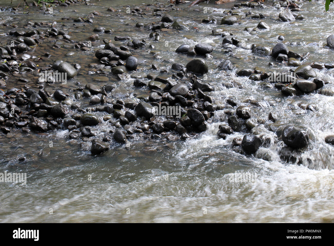 Close up of gently rushing water over slippery, wet pebbles at Ho'olawa ...