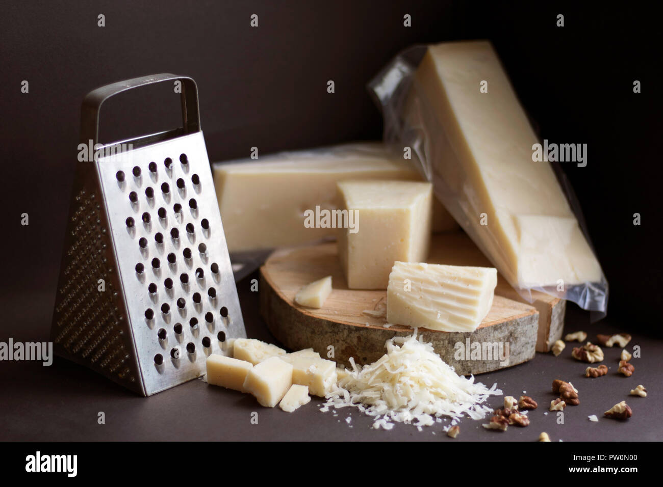 Dark background with grater and different pieces of cheese Stock Photo ...