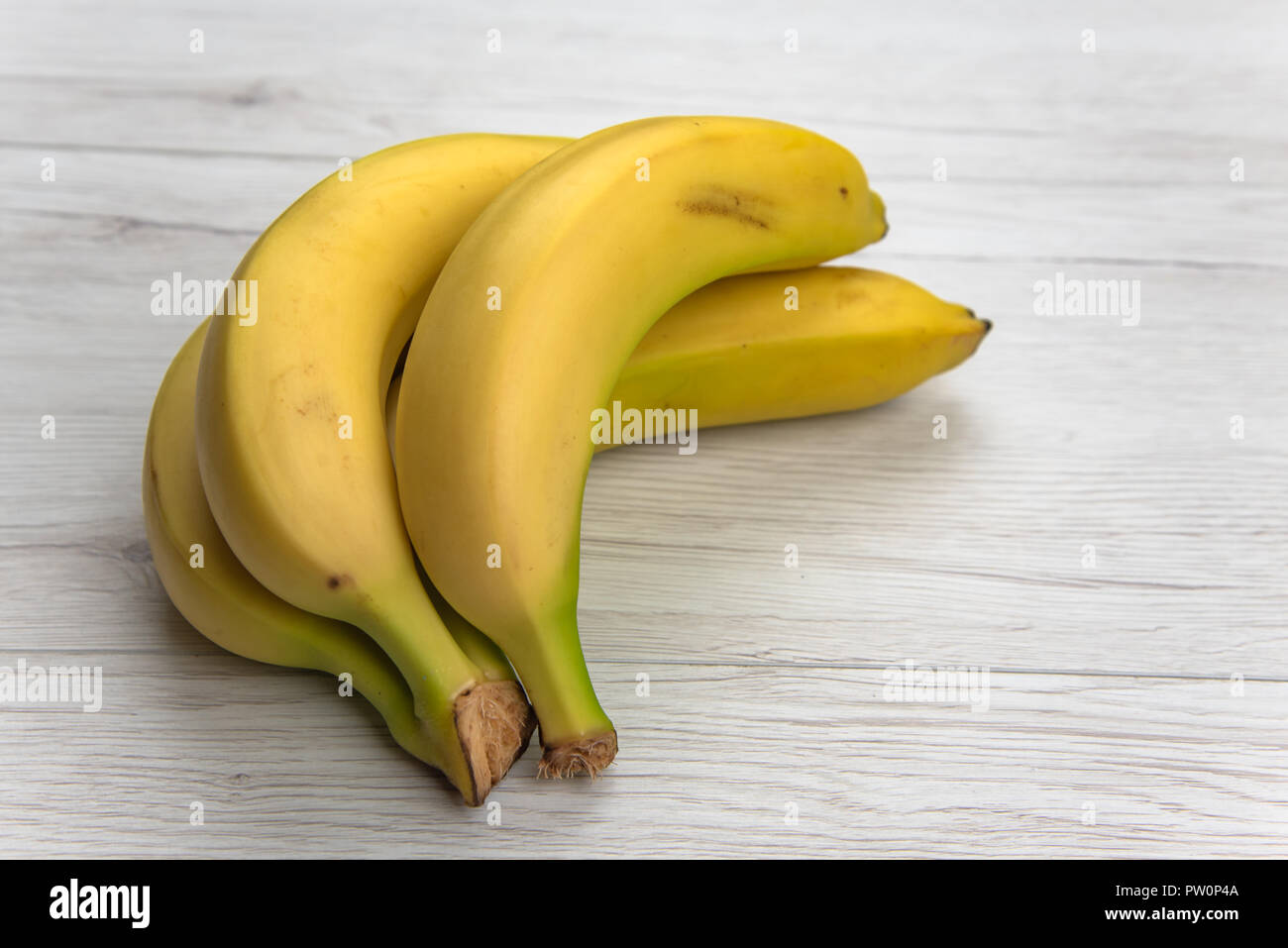 Bananas on white wood table, isolated Stock Photo - Alamy