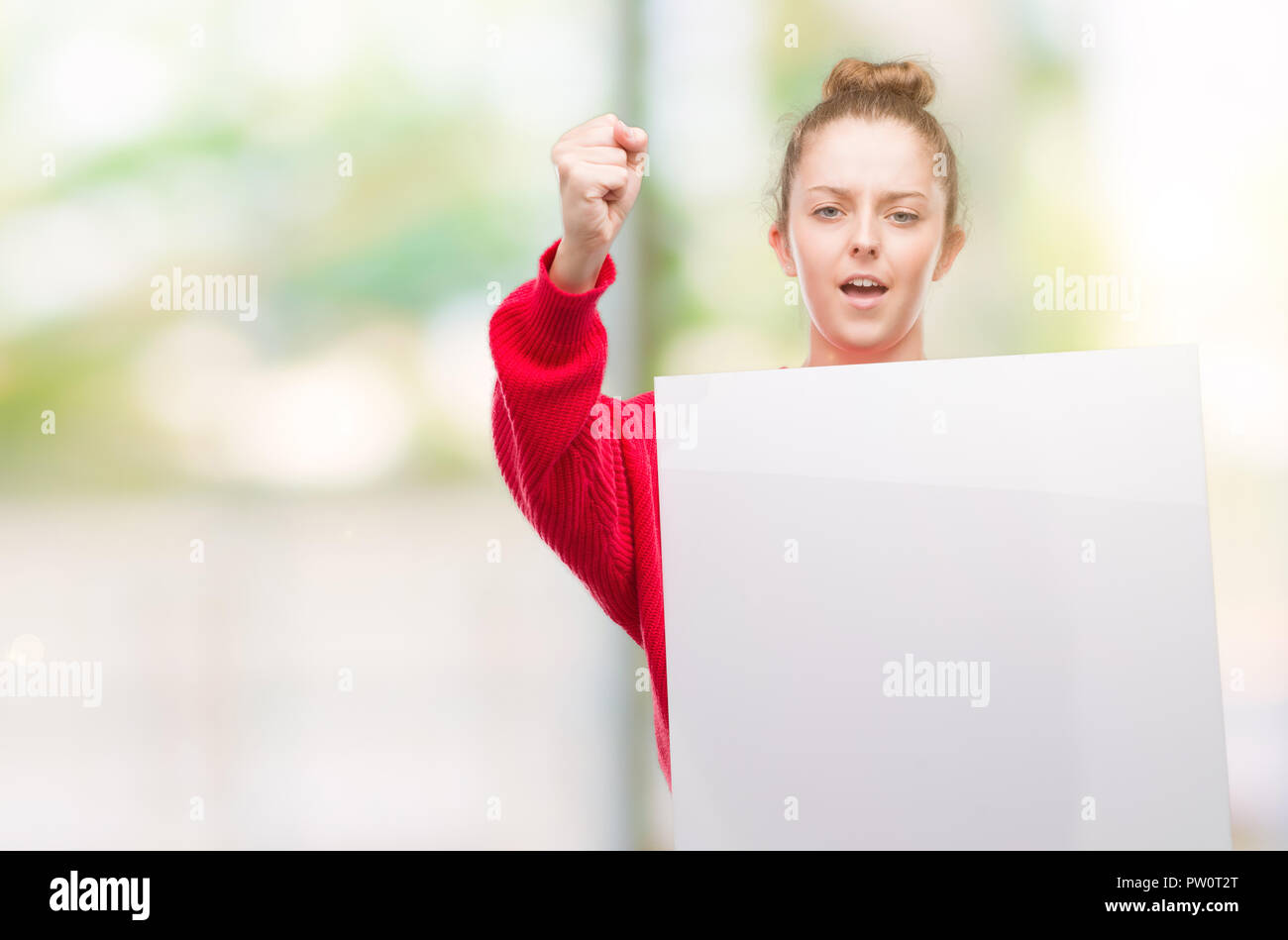 Young blonde woman holding advertising banner annoyed and frustrated ...
