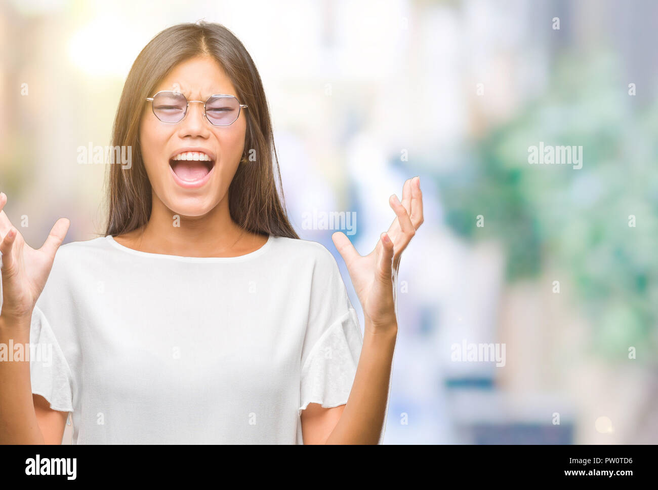 Young asian woman wearing glasses over isolated background crazy and ...