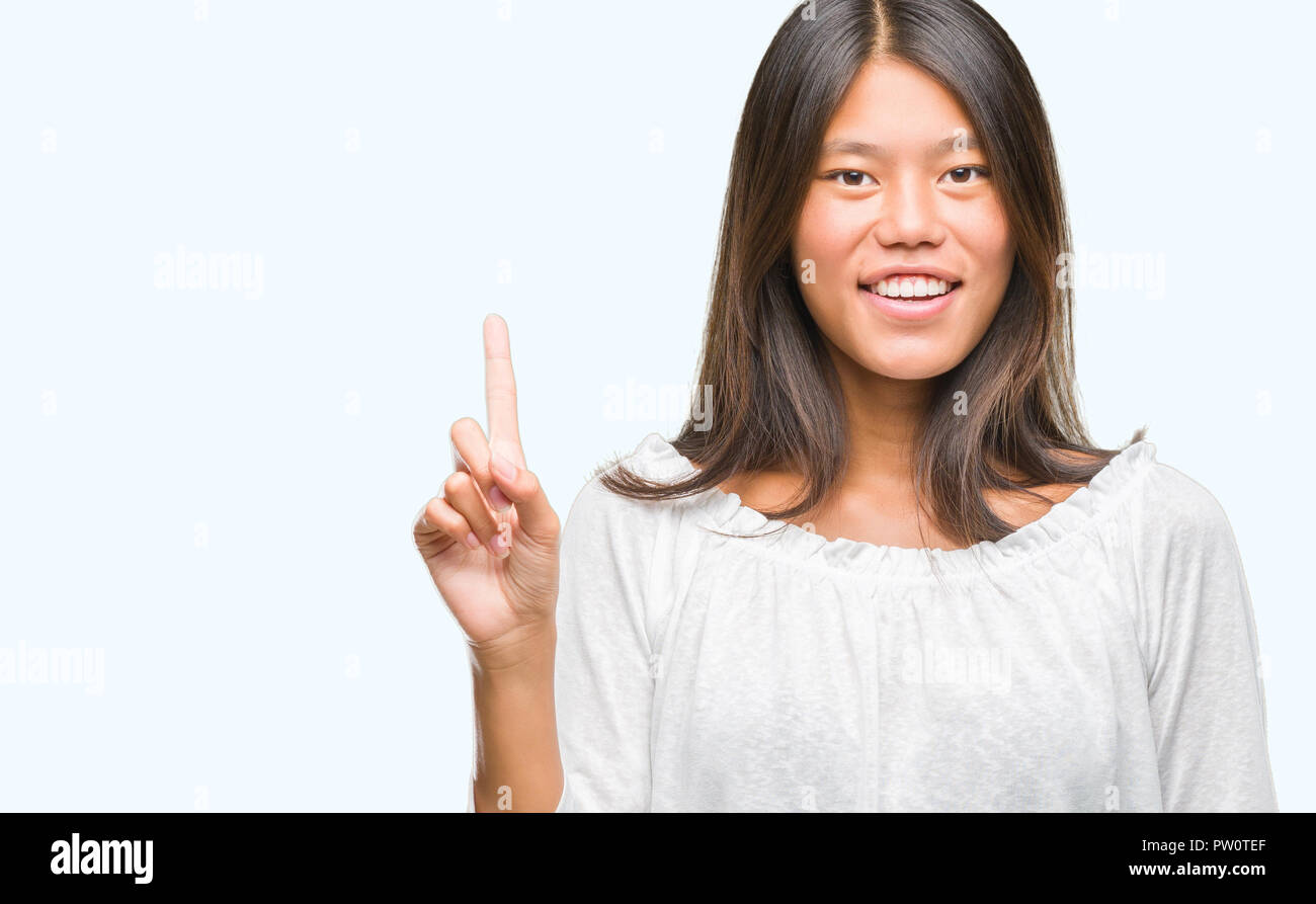 Young asian woman over isolated background showing and pointing up with ...