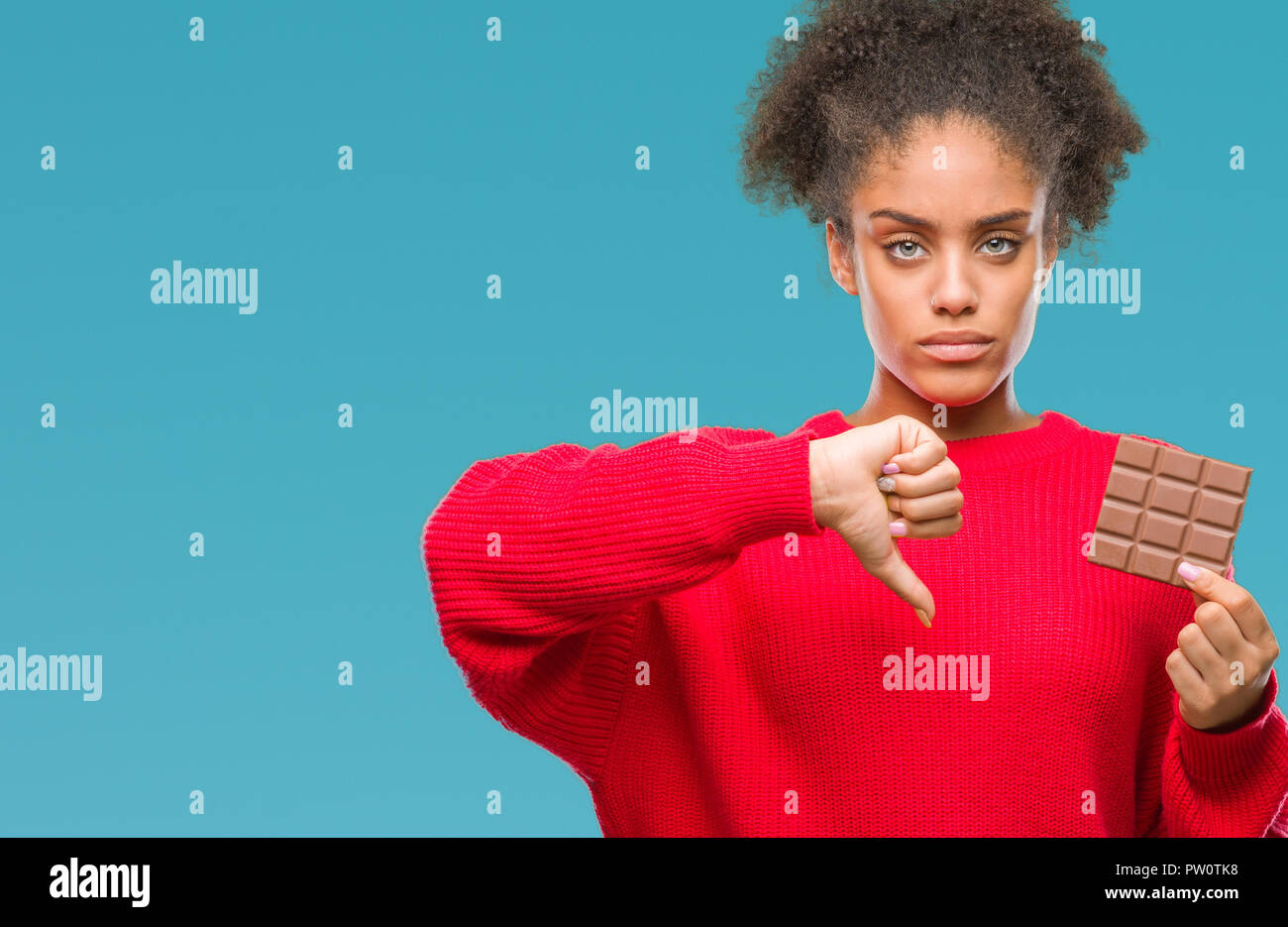 Young afro american woman eating chocolate bar over isolated background ...