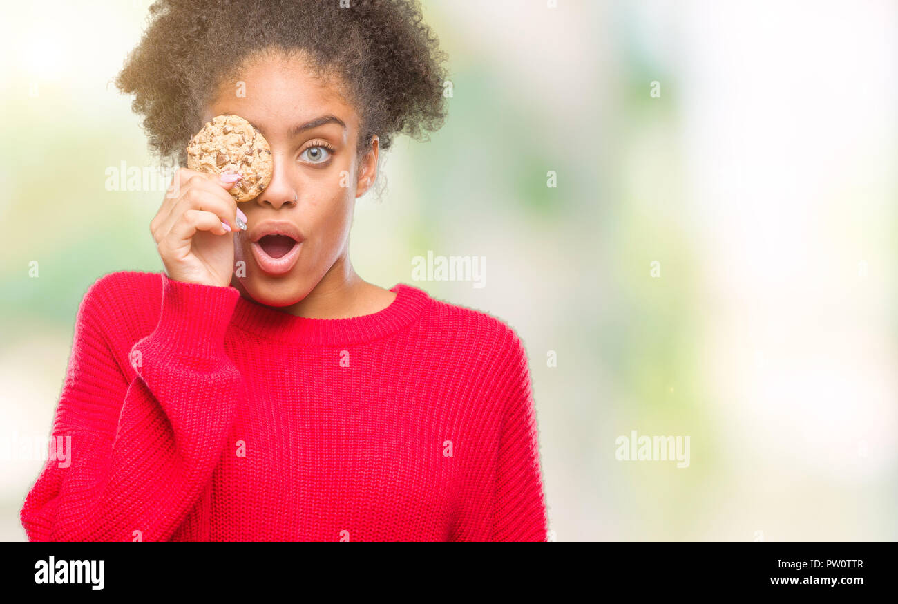 Young afro american woman eating chocolate cookie over isolated ...