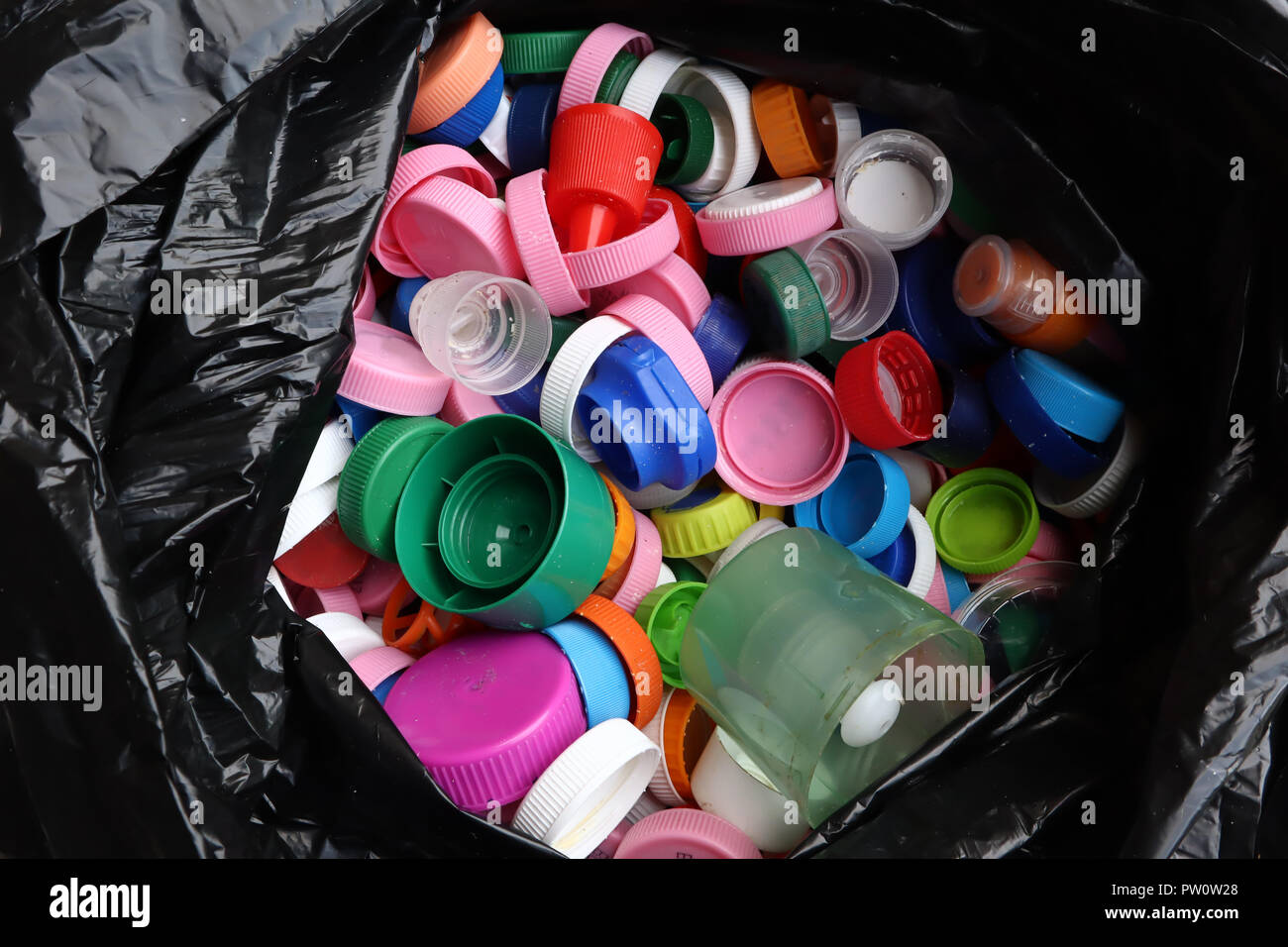 group of multicolored bottle caps in black plastic bag, ready for ...