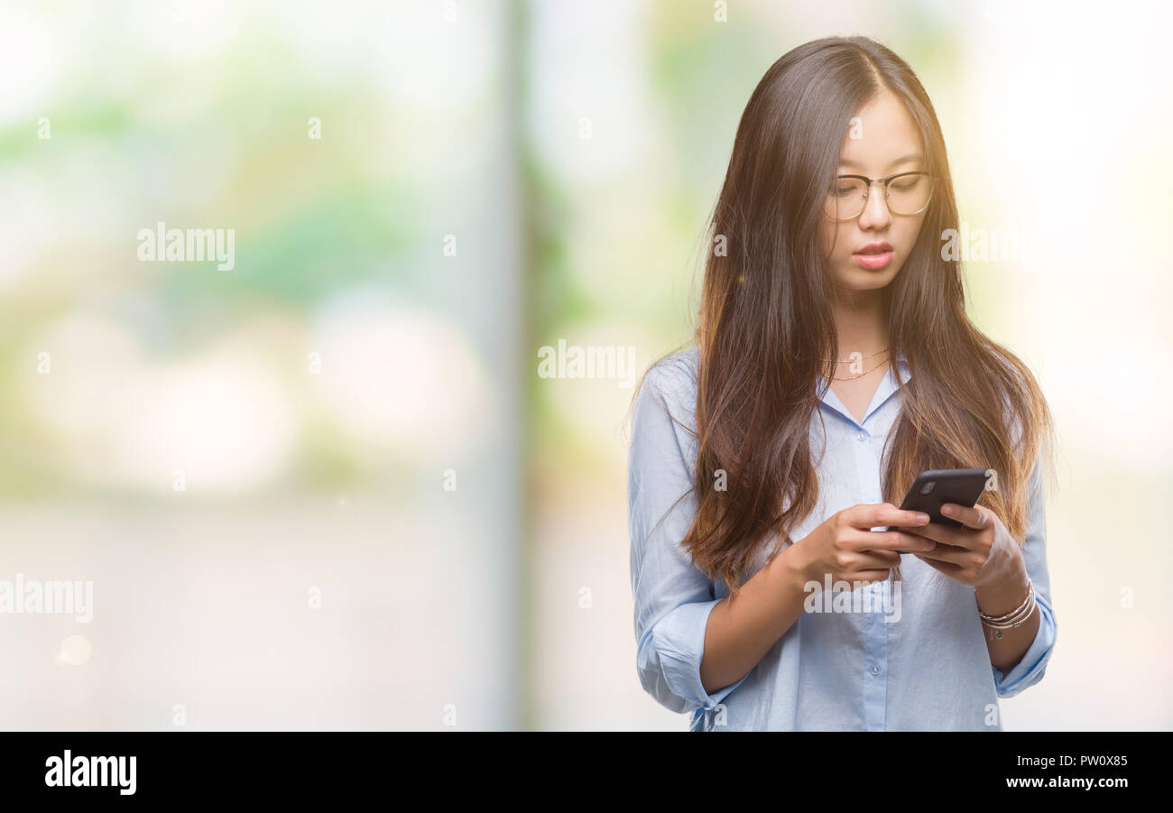 Young asian woman texting using smartphone over isolated background ...