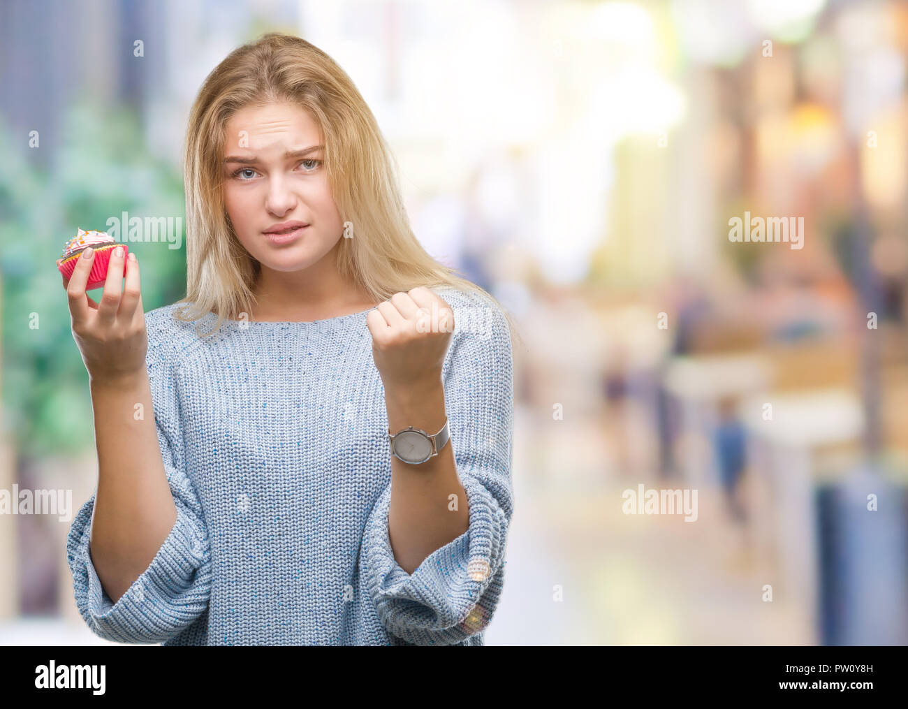 Young caucasian woman eating sweet cupcake over isolated background ...