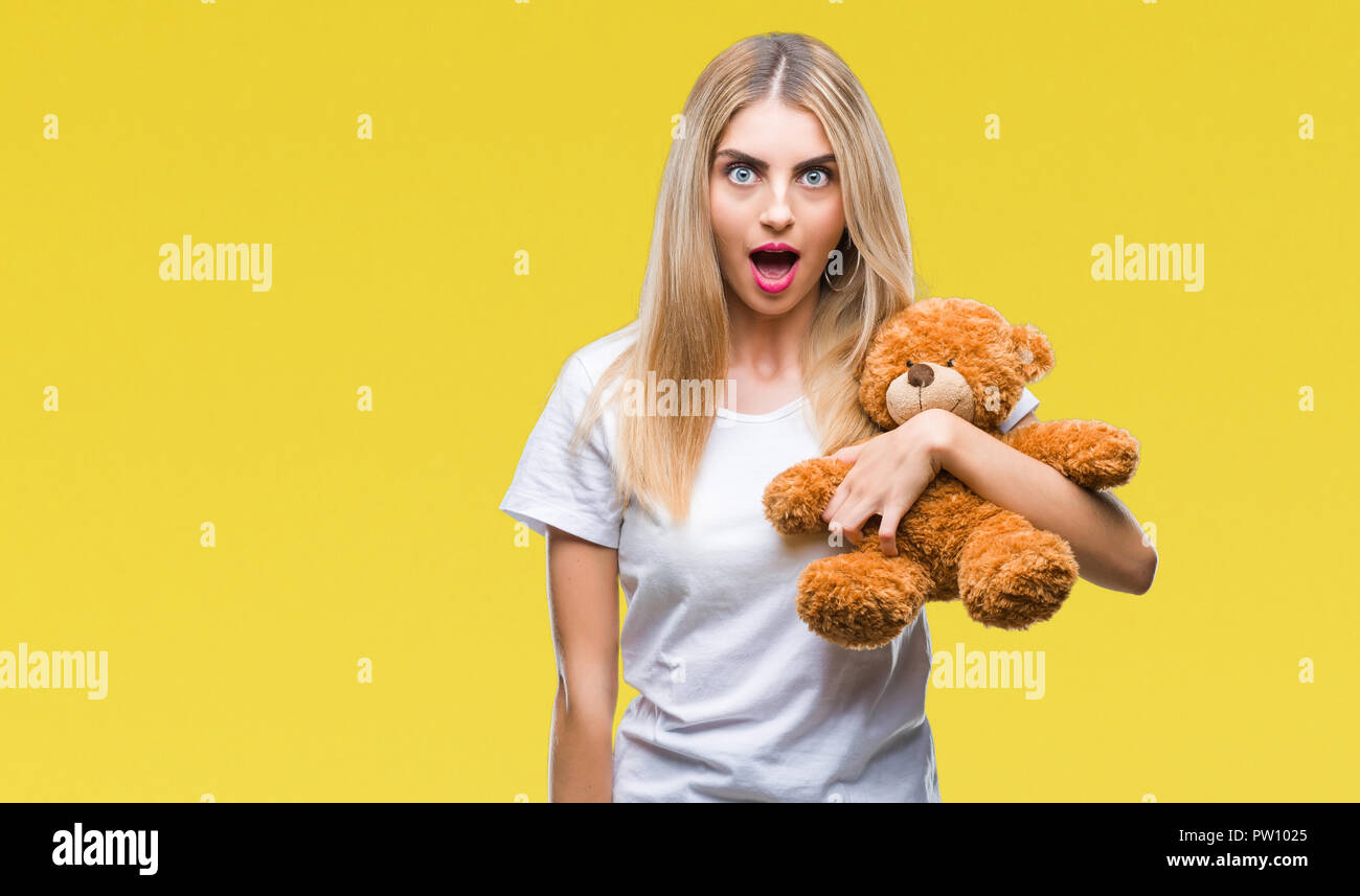 Young beautiful blonde woman holding teddy bear over isolated ...